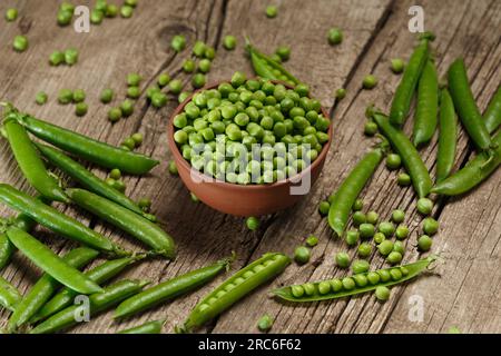 A pile of fresh green peas, some shelled and some still in their pods ...