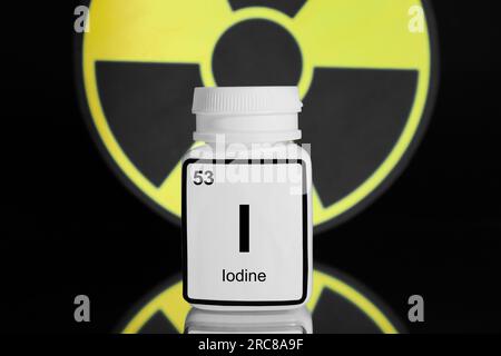 Bottle of medical iodine, radiation sign and pills on light blue ...