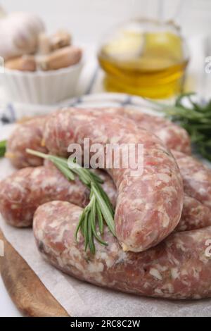 Raw sausages or bratwurst on parchment paper and ingredients for ...