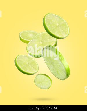 Fresh lime slices falling on light green background Stock Photo - Alamy