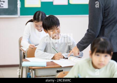 A boy being taught by his teacher during class Stock Photo - Alamy