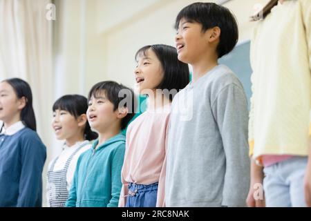 Elementary school students singing a song in front of the blackboard ...