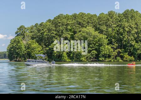 Pontoon boat pulling inflatable tube float raft on lake. Family on a ...