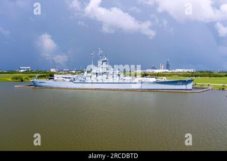 An aerial port view of the battleship USS IOWA (BB 61) firing to starboard from its No. 1 Mk 7 ...