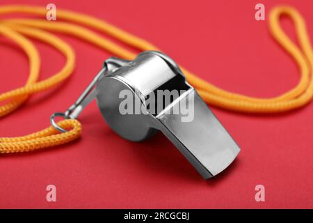 One metal whistle with red cord on light green background, top view ...
