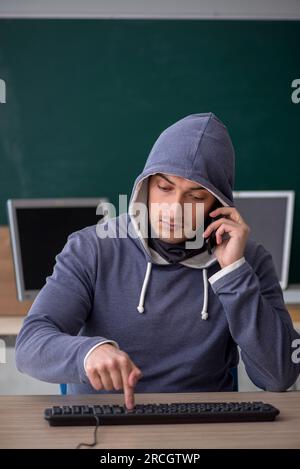 Young hacker sitting in the classroom Stock Photo - Alamy