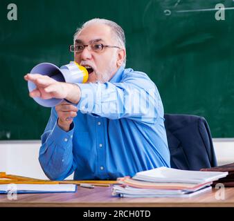 Angry male math teacher holding megaphone Stock Photo - Alamy