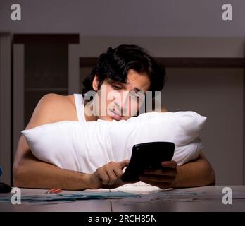 Young man calculating expences night at home Stock Photo - Alamy