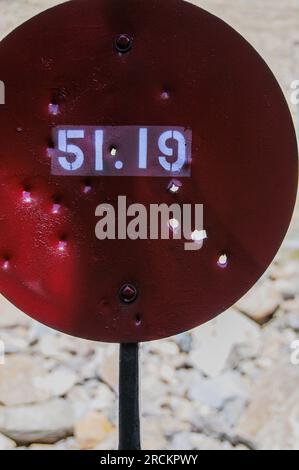 Target practice gun shots and bullet holes on red railway sign in ...