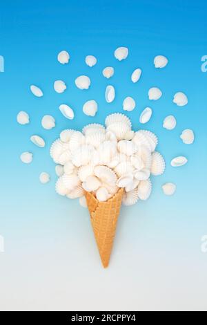 Ice cream cone with sea shells and starfish over blue background ...