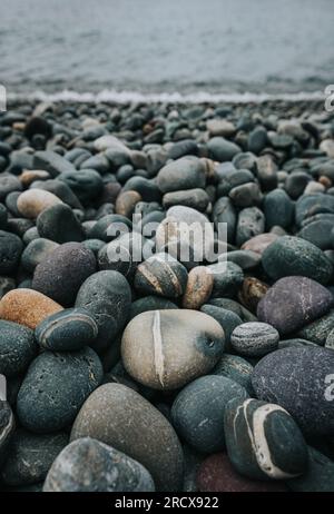 Colorful smooth rocks on the beach covered in water Stock Photo - Alamy