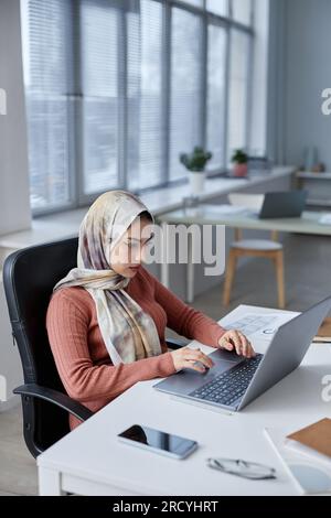 Young serious female broker or analyst making notes during data ...