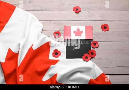 Poppy flowers with flags of Canada and card on grunge pink background ...
