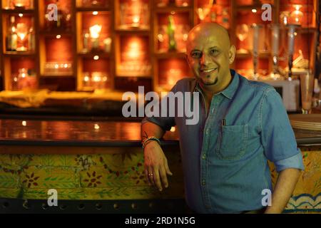 Young and flamboyant handsome bald guy standing on bar counter ...