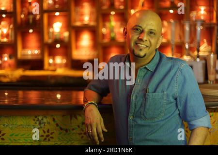 Young and flamboyant handsome bald guy standing on bar counter ...