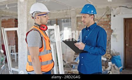 Two men builder and architect writing document speaking at construction ...