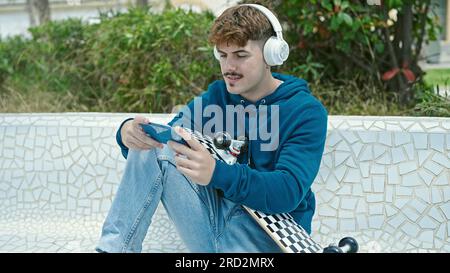 Handsome hispanic man playing video games with smartphone looking ...