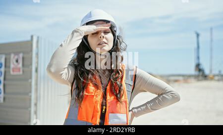 Young beautiful hispanic woman architect writing on notebook at street ...