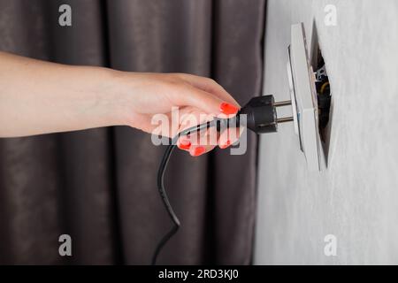 The girl removes the electrical plug from the socket and breaks the ...