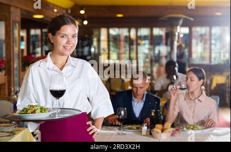 Waiter standing with serving tray, recommending dishes in restaurant ...
