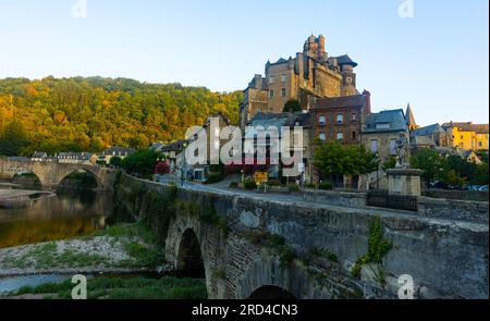 French township of Estaing on bank of Lot River with arched bridge and ...