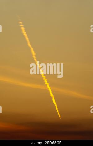 Airplane vapor trail (contrail) across the golden sky at sunset Stock ...