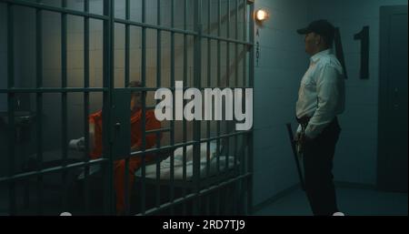 Jailer gives phone to female prisoner. Woman criminal in orange uniform ...