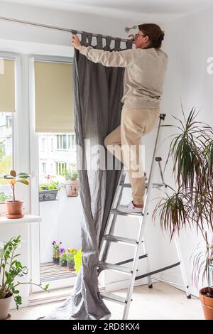 woman on ladder hanging curtains at home Stock Photo - Alamy