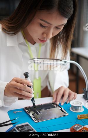 Woman using a magnifying glass to check the authenticity of a leather ...