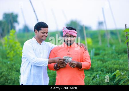 Indian farmer giving money to his worker , smart farmer, young farmer ...