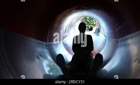 Mother sliding down inside playground tunnel slider Stock Photo - Alamy