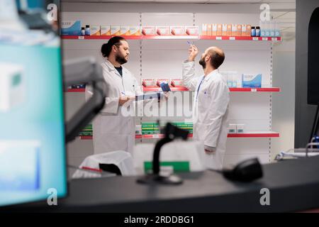 Two men pharmacists doing medicaments inventory checking drugs packages ...