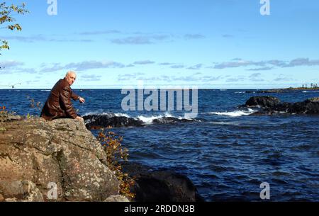 Older male sits on the edge of a wooden dock over Cooty Lake in ...