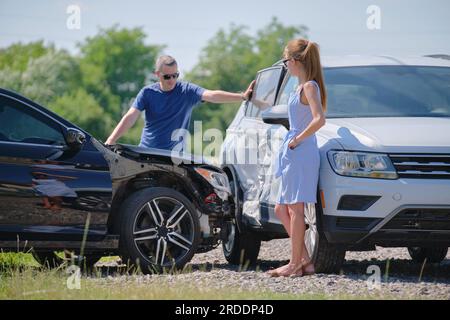 Angry woman and man drivers of heavily damaged vehicles arguing who is ...