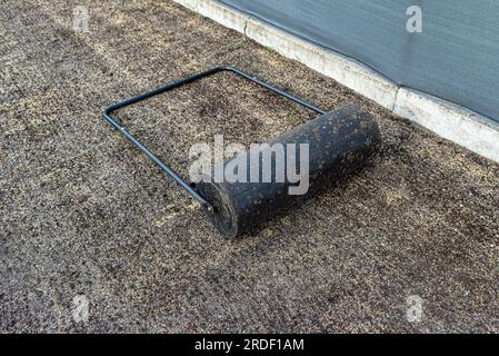 Rolling freshly sown grass seeds with a metal roller filled with water ...