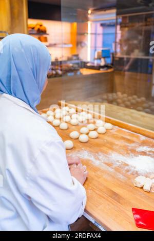 Arab woman baker in the bakery workshop workshop of artisan bakery preparing the bread dough ...