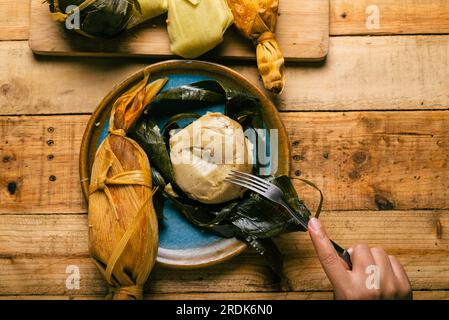 Hands of a person cutting a tamale with a fork. Tamale, typical Mexican ...