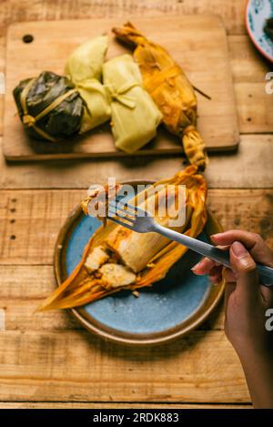 Hands of a person cutting a tamale with a fork. Tamale, typical Mexican ...