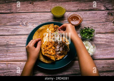 Hands of a person preparing a gringa pastor a la diabla accompanied by ...