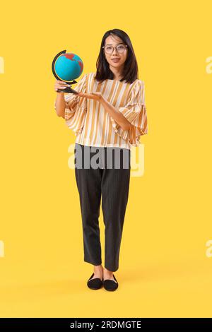 Female Asian Geography teacher with globe on yellow background Stock ...