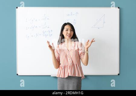 Asian Math teacher near flipboard in classroom Stock Photo - Alamy