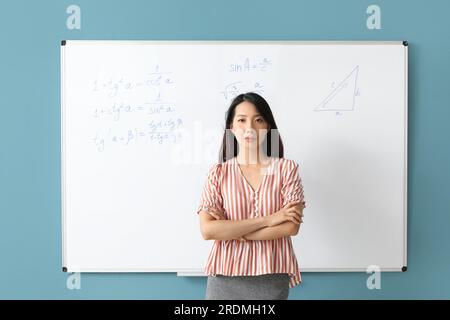 Asian Math teacher near flipboard in classroom Stock Photo - Alamy