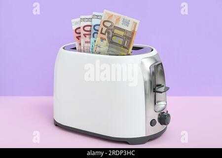 Toaster with euro banknotes on table near lilac wall Stock Photo - Alamy