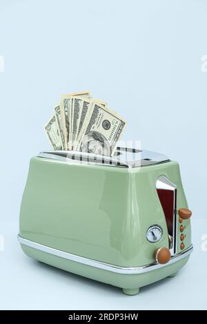 Toaster with dollar banknotes on light background Stock Photo - Alamy