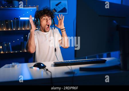 Shocked arabic gamer in headset at night near computer staring at ...