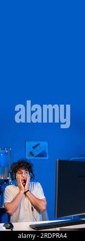 Shocked arabic gamer in headset at night near computer staring at ...