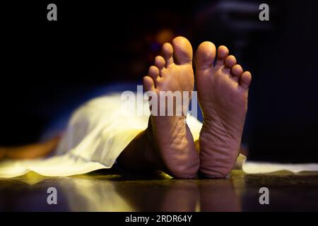 Feet of an Indian or Asian female dead body lying on floor in a dark ...