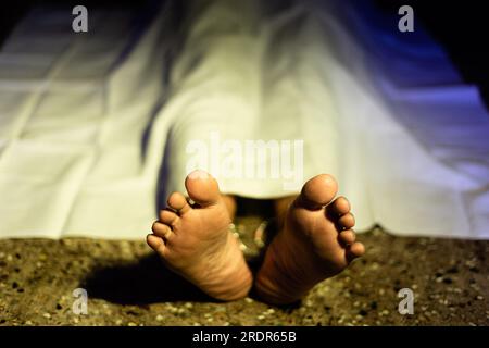 Feet of an Indian or Asian female dead body lying on floor in a dark ...