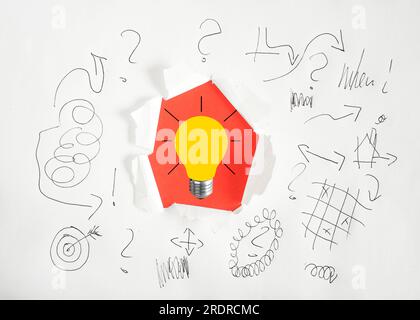 Lightbulb inside of punch paper with scribble and question marks for ...