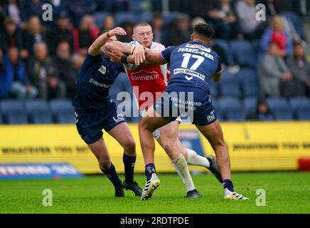 Hull KR' James Batchelor (centre) attempts to run between Wigan ...